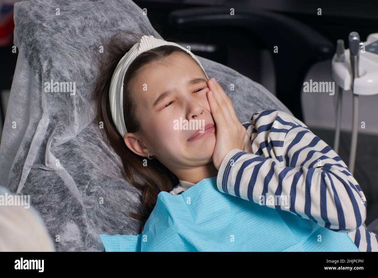 Small girl pointing at painful tooth site during appointment with his ...