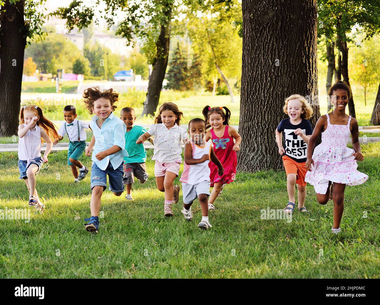 a group of preschoolers running on the grass in the Park Stock Photo ...
