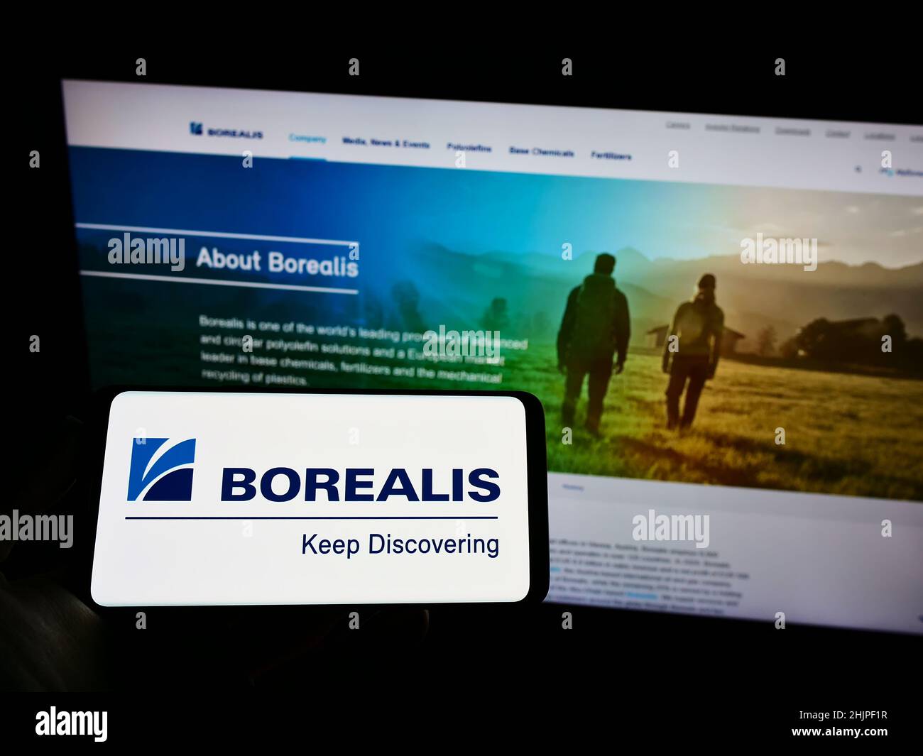 Person holding smartphone with logo of Austrian chemical company Borealis AG on screen in front ...