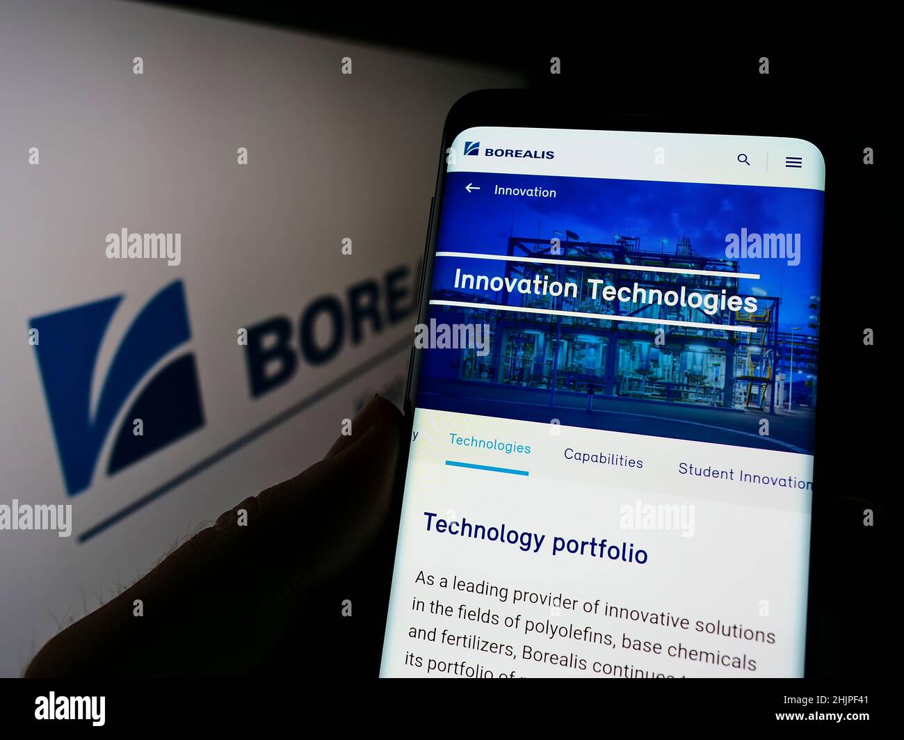Person holding cellphone with webpage of Austrian chemical company Borealis AG on screen in ...