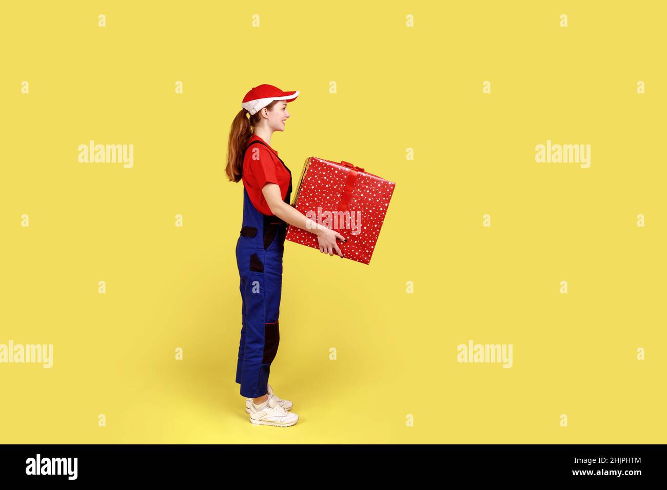 Side view portrait of courier woman standing with big present box in ...