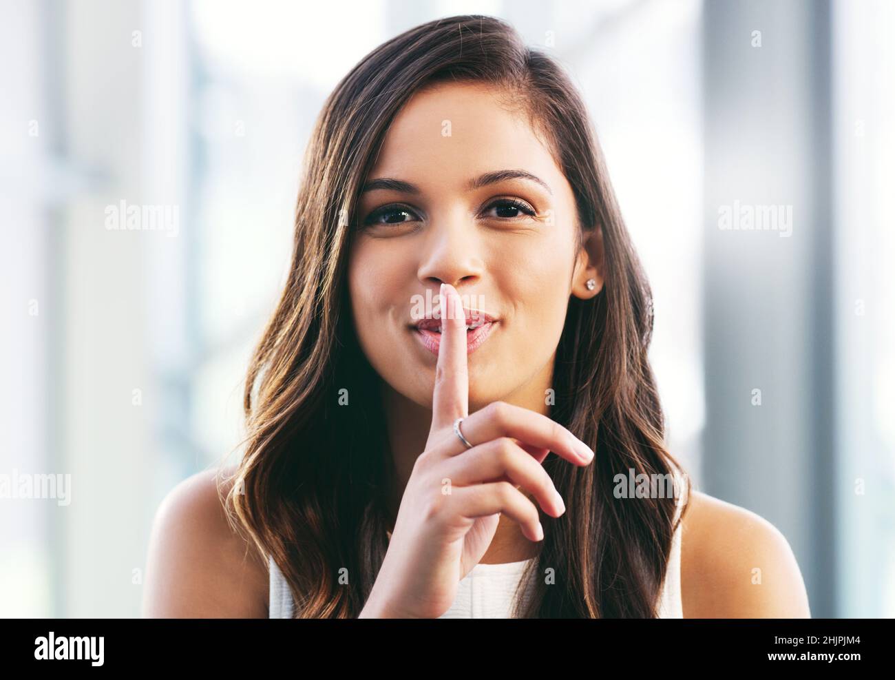 Don't tell anyone, but.... Portrait of a young businesswoman placing ...