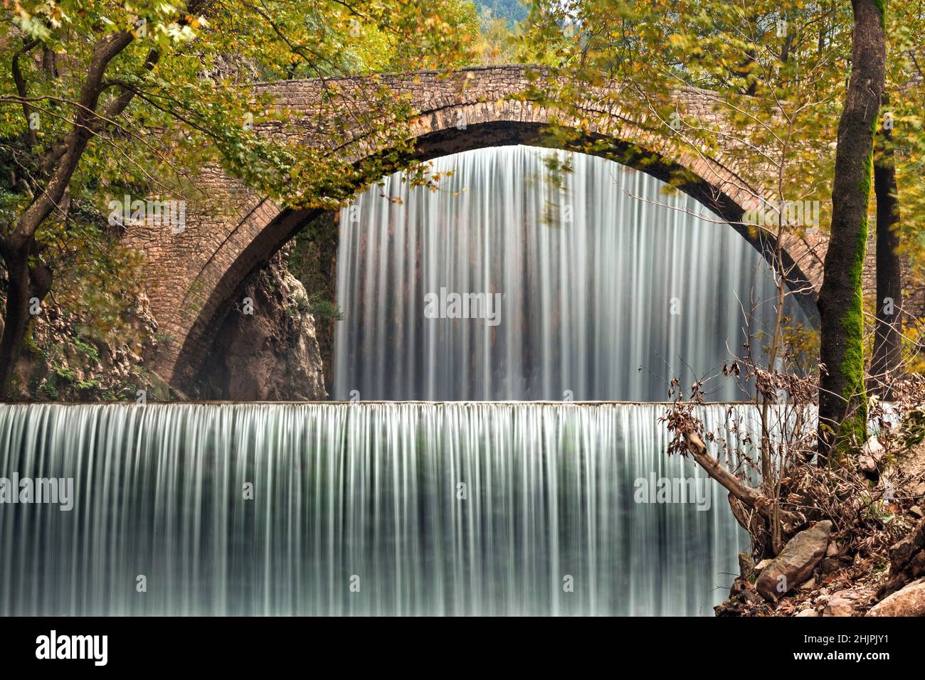 The old stone, arched bridge, between two waterfalls in Palaiokaria ...