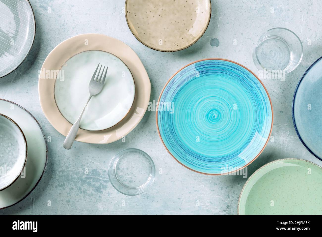 Modern tableware set with cutlery and a vibrant blue plate, overhead ...