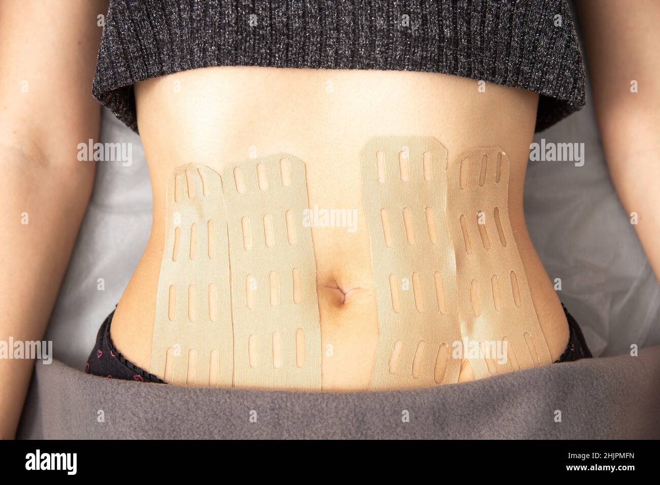 Young caucasian girl with kinesiology tape on her belly. A professional ...