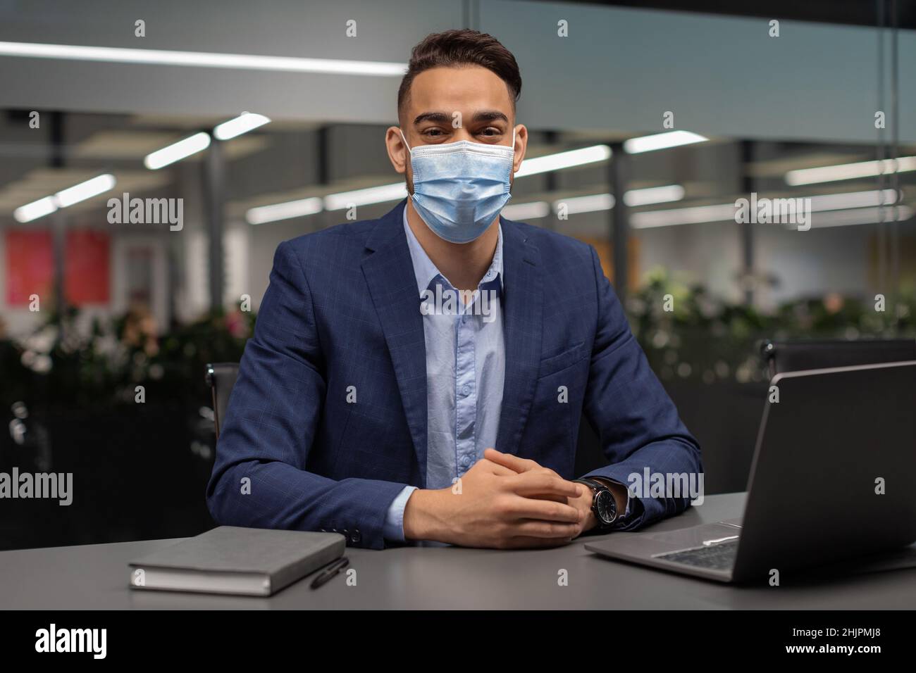 Arab manager in face mask sitting at worktable with computer Stock ...
