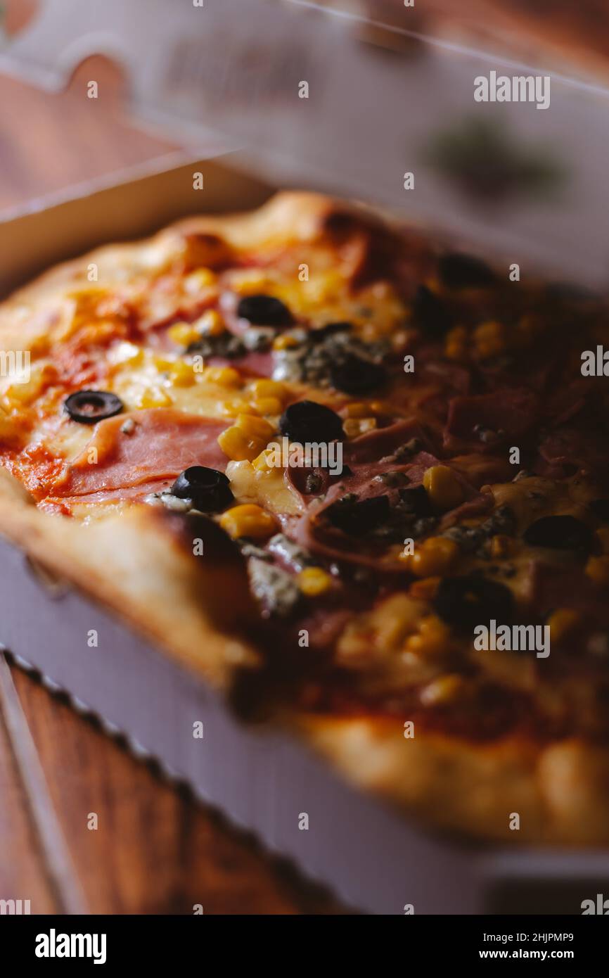 Vertical shot of a pizza with tomato base and different toppings in a ...