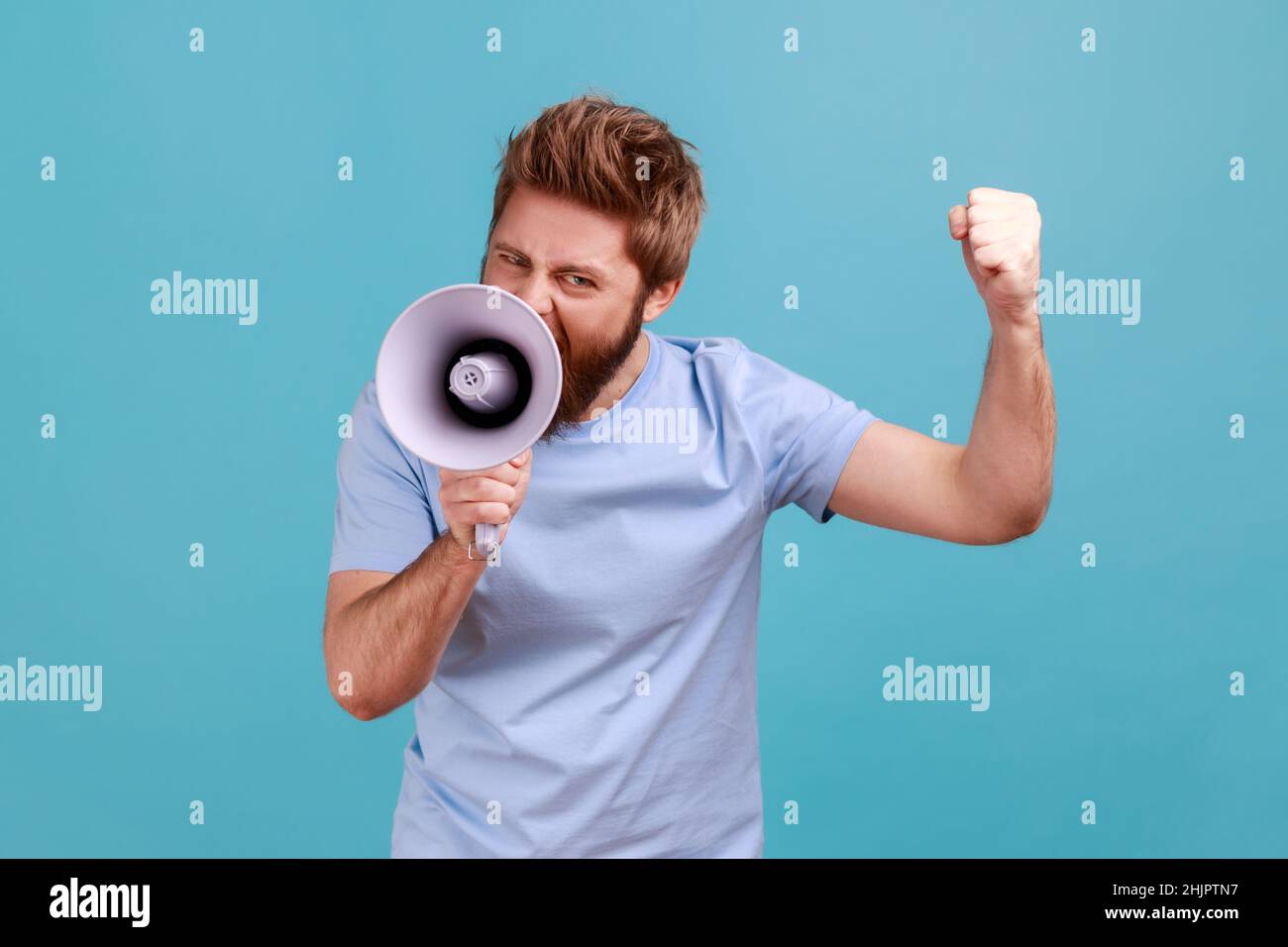 Portrait of aggressive bearded man holding megaphone near mouth, loudly ...