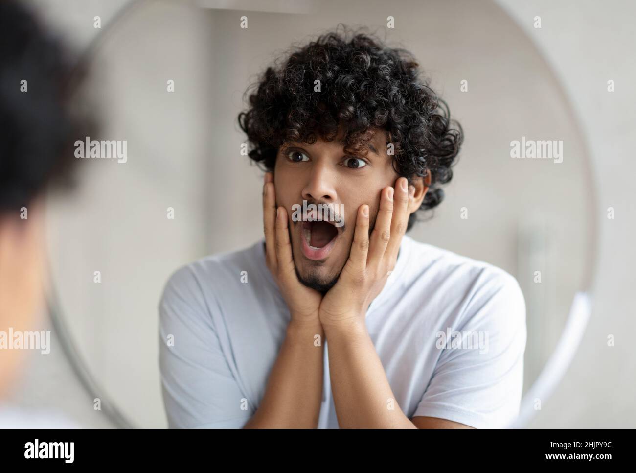 Skin problems concept. Shocked indian man looking at mirror and ...