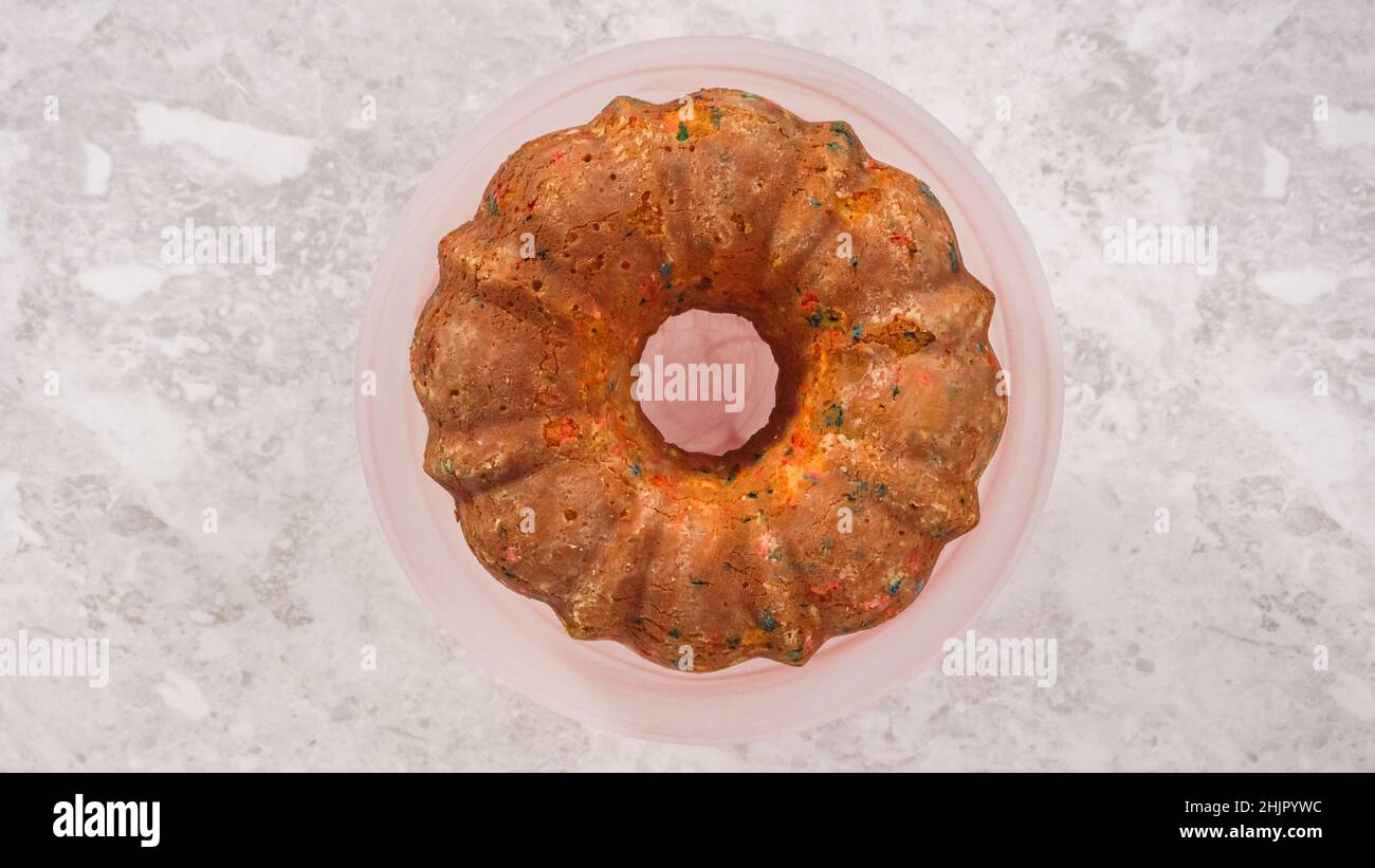Flat lay. Step by step. Frosting funfetti bunt cake with pink ...