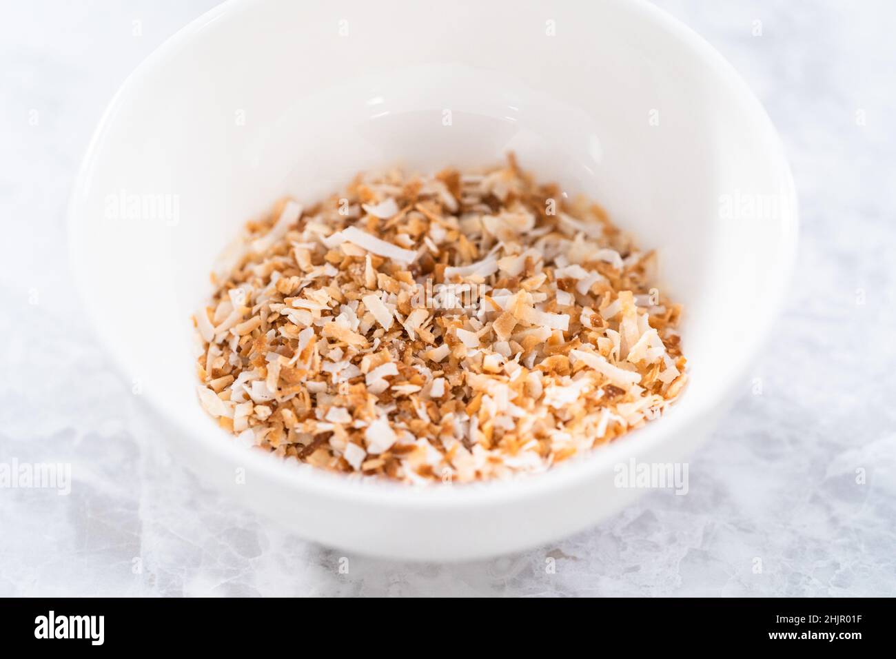 Toasted shredded coconut flakes in a white ceramic bowl Stock Photo - Alamy