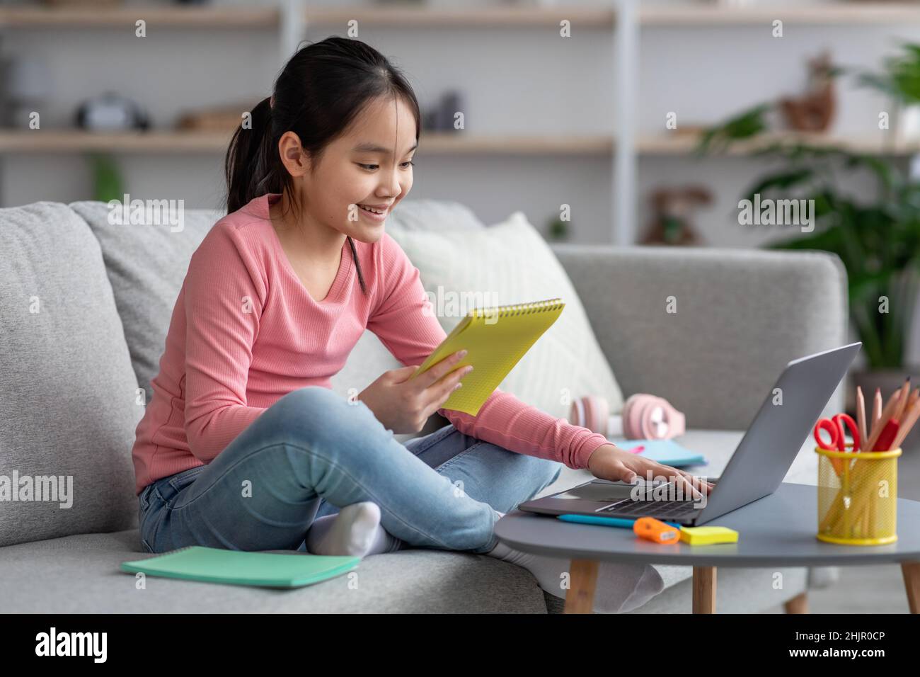 Happy asian girl doing homework, using laptop Stock Photo - Alamy
