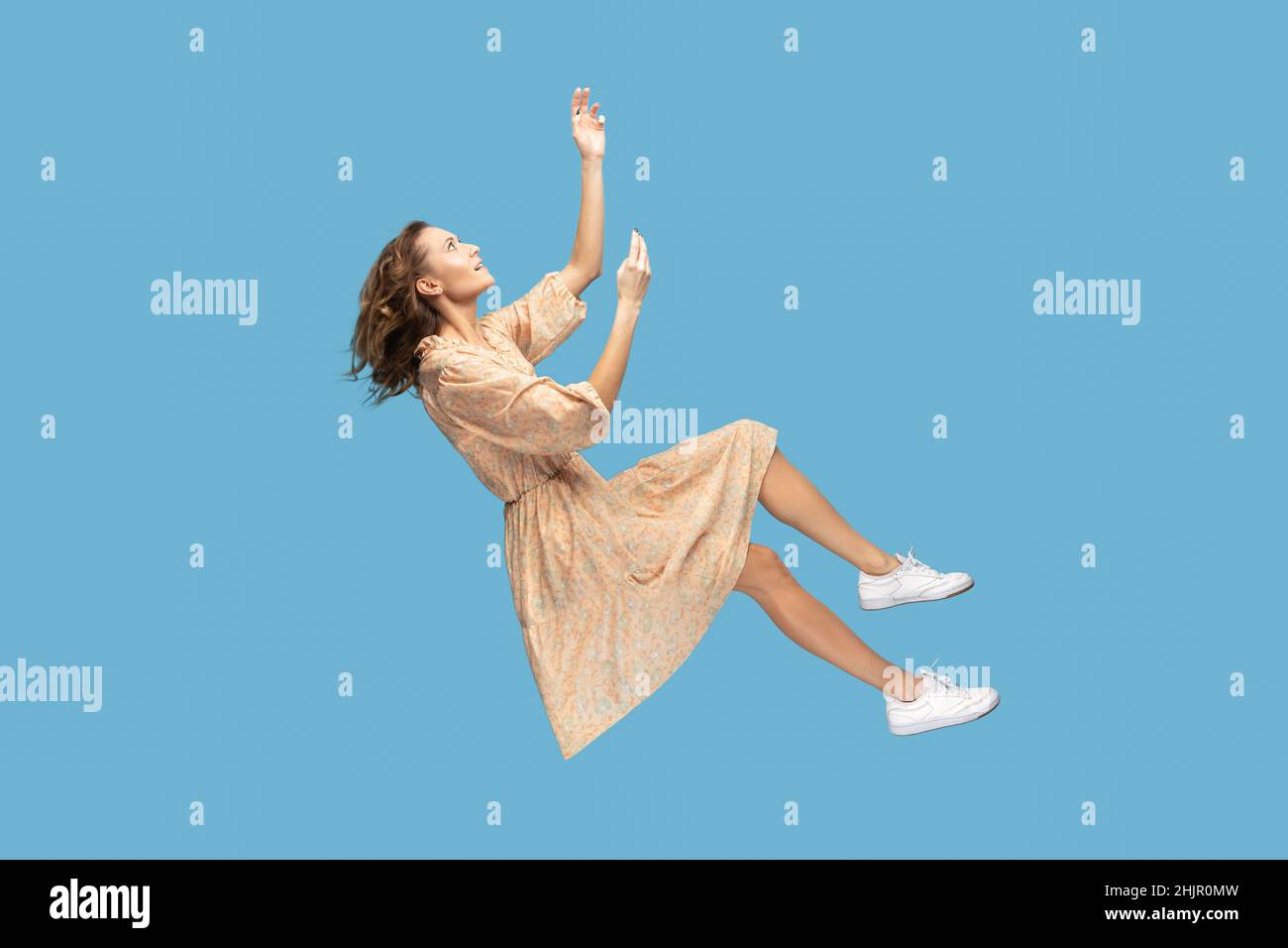 Hovering in air. Relaxed beautiful girl in yellow dress and curly ...