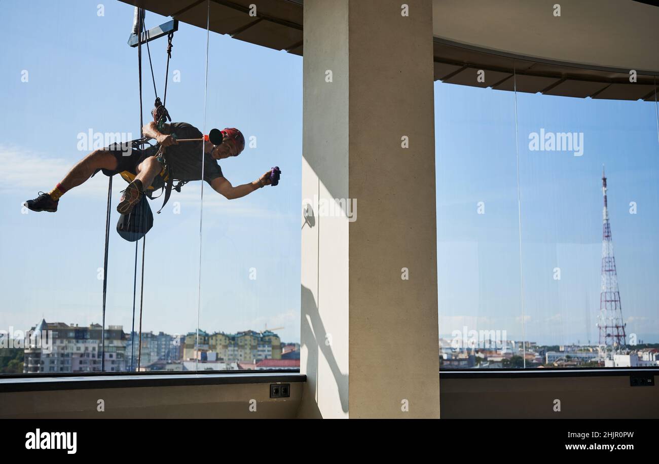 Industrial mountaineering worker professional cleaner hanging on ...