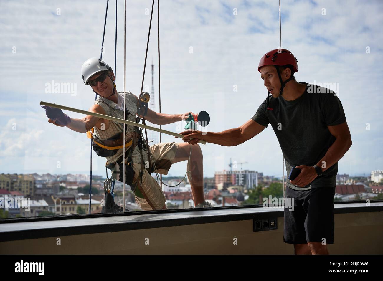 Industrial mountaineering professional cleaner hanging on rope and ...