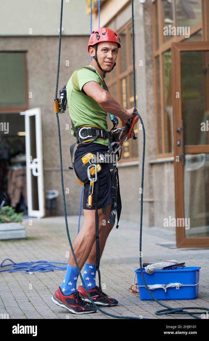 Industrial mountaineering worker in safety helmet holding climbing rope ...