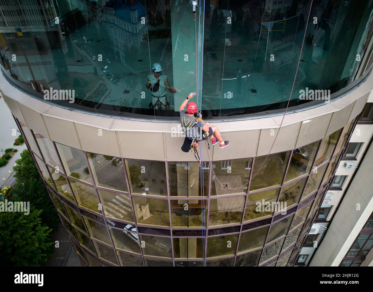 Industrial mountaineering worker cleaning window of high-rise building ...