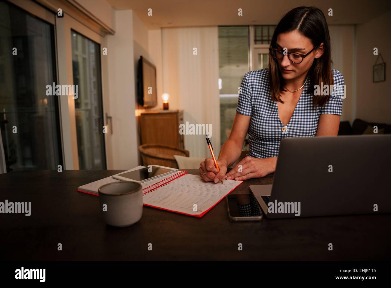 Caucasian female working late at night writing down dates in calendar ...