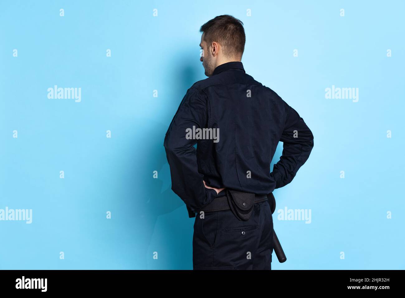 Back view of young man, policeman officer wearing black uniform ...