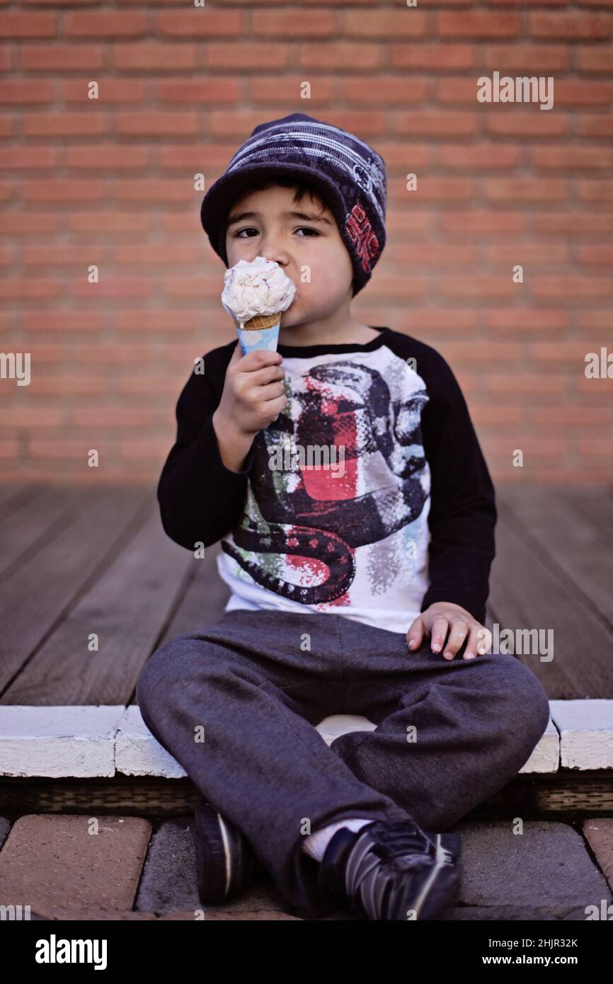 Boy eating ice cream in front of a brick wall Stock Photo - Alamy