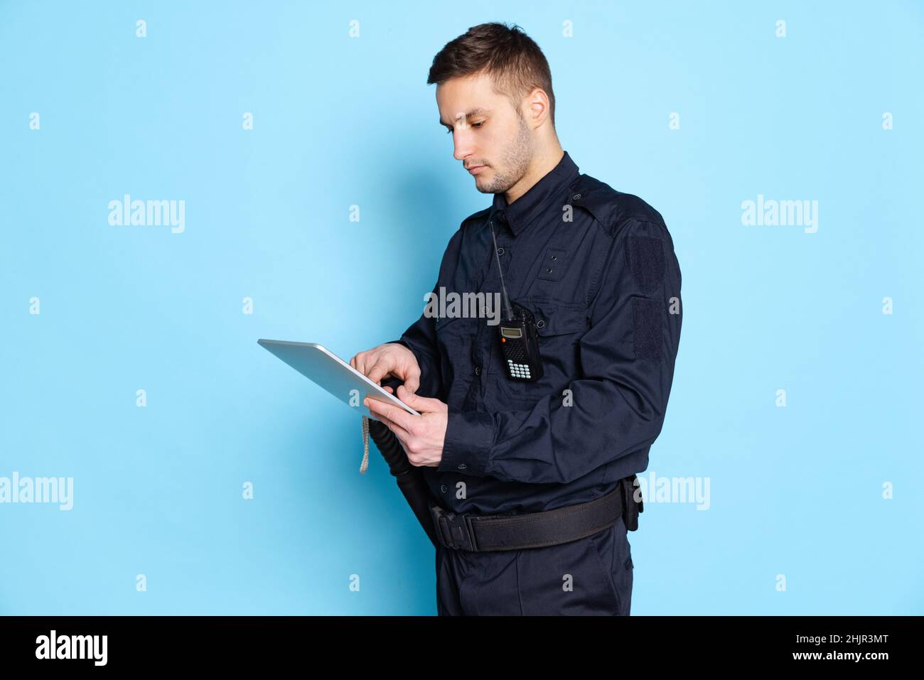Portrait of young man, policeman officer wearing black uniform using ...