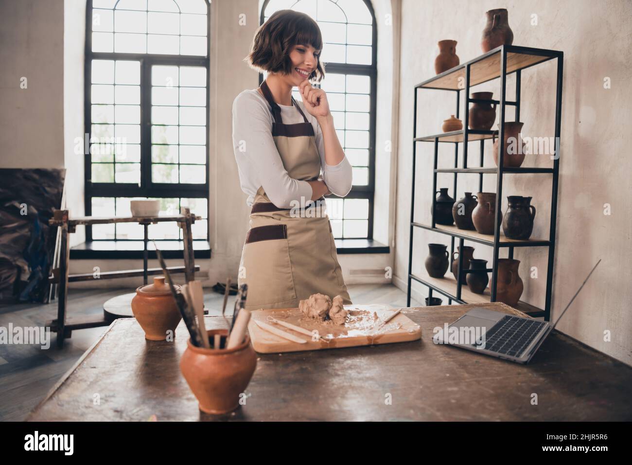 Photo of inspired lady potter stand in workroom use netbook watch ...
