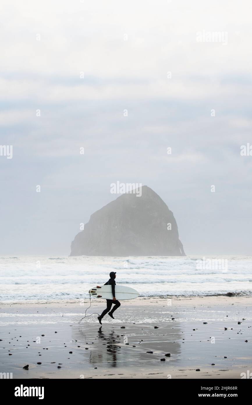 Female surfer running to catch waves is Coastal Oregon Stock Photo - Alamy