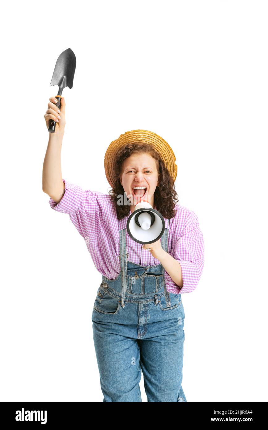 Young beautiful girl, female gardener in work uniform and hat shouting ...
