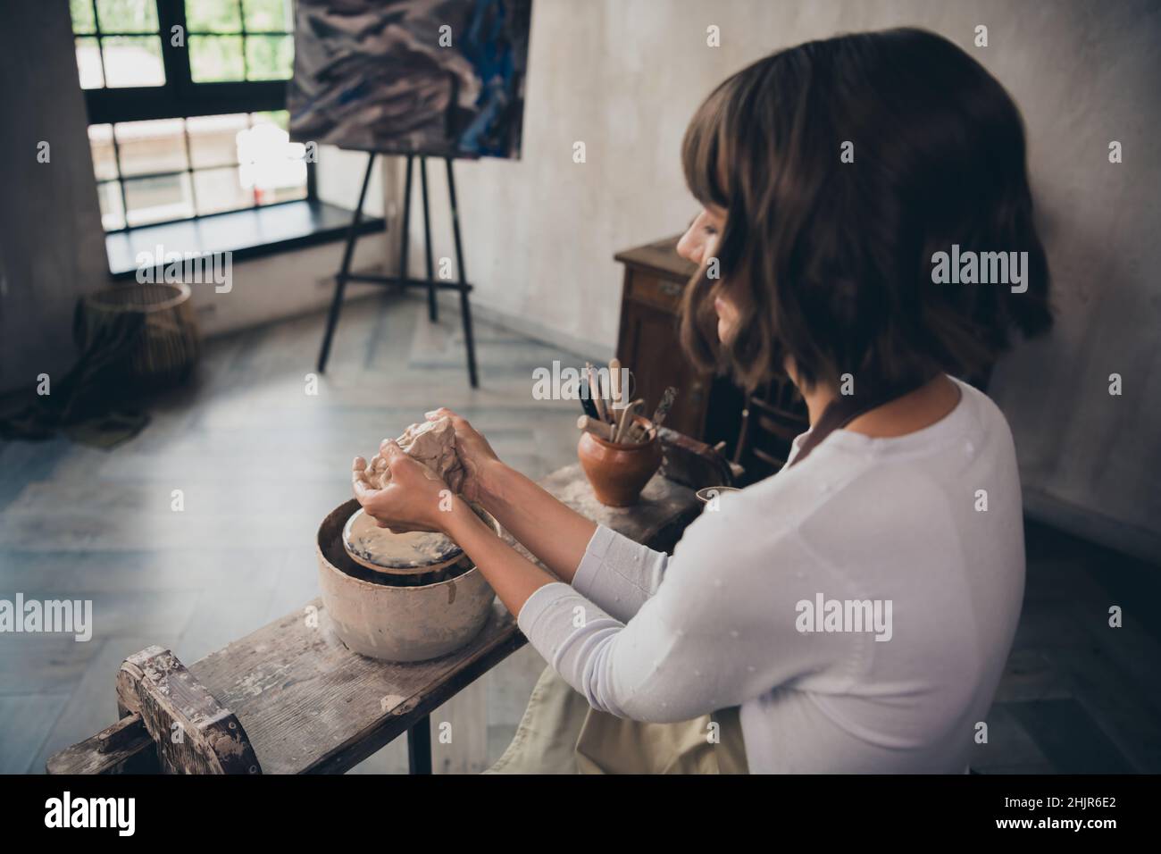 Back rear spine photo of pottery owner self-employed lady doing pot mud ...