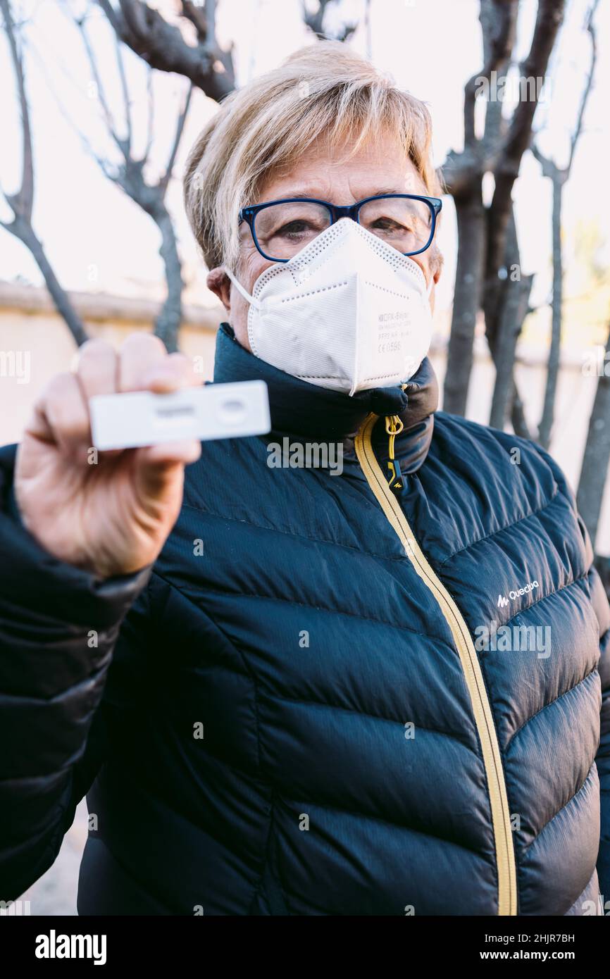 Elderly lady on the street, wearing a white mask, with a negative ...