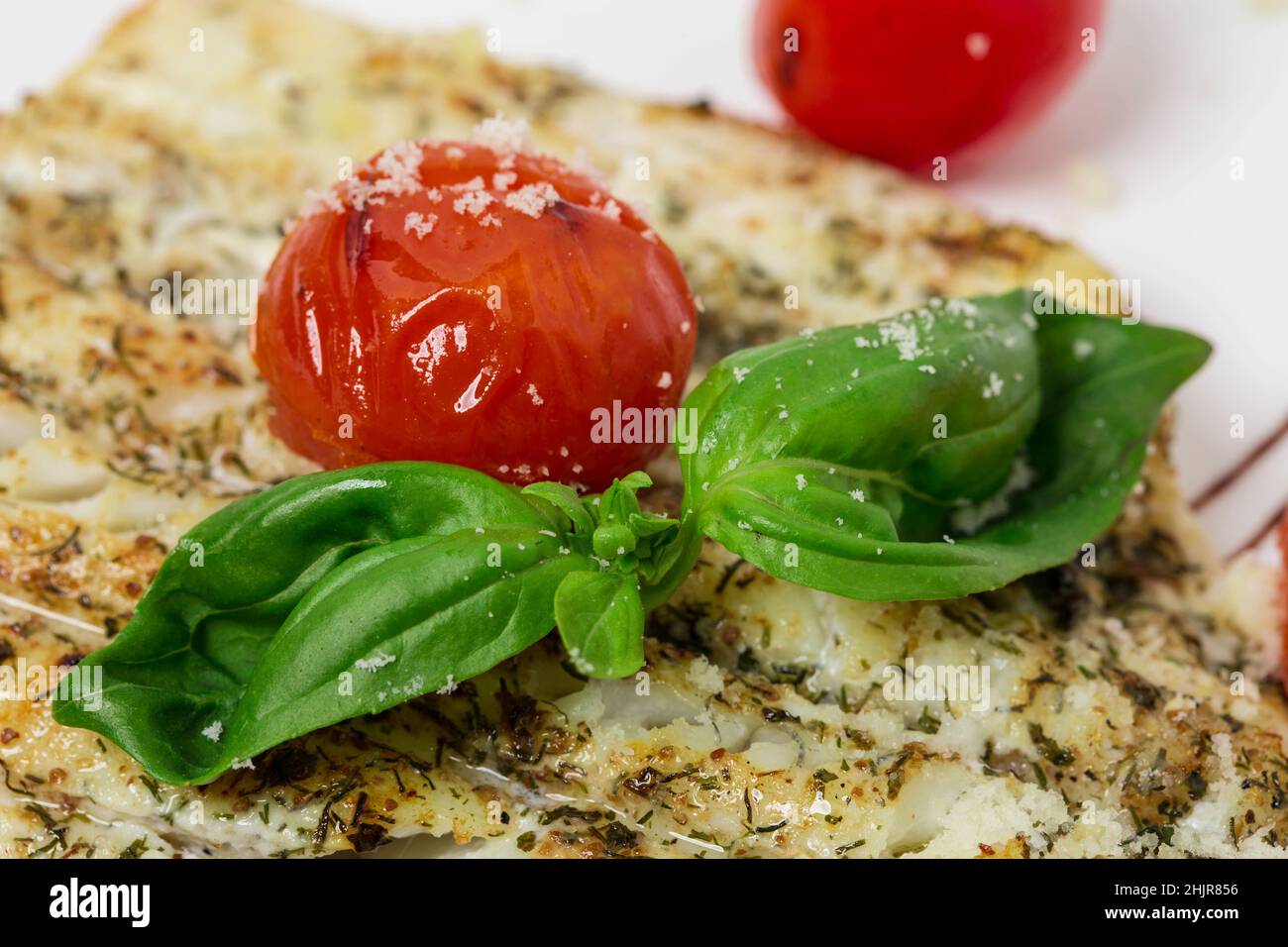 Baked fish fillet with tomatoes and basil. Macro. Can be used as a ...