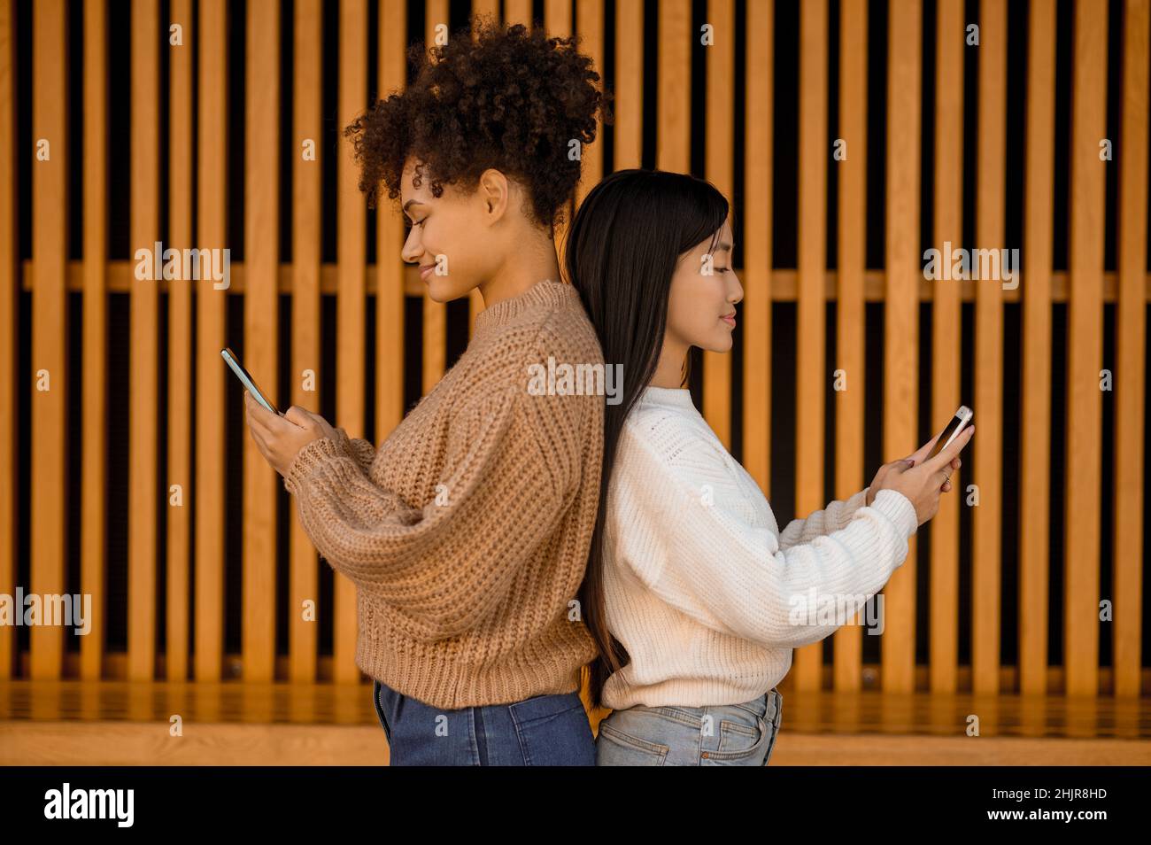 Two girls touching their backs sideways to camera Stock Photo - Alamy