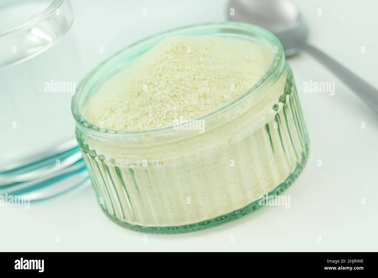 Collagen powder and glass of water with spoon Stock Photo - Alamy