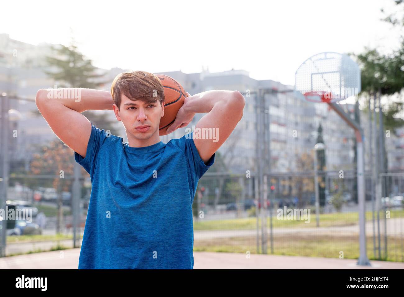 portrait of a young man on a basketball court holding a basketball ...