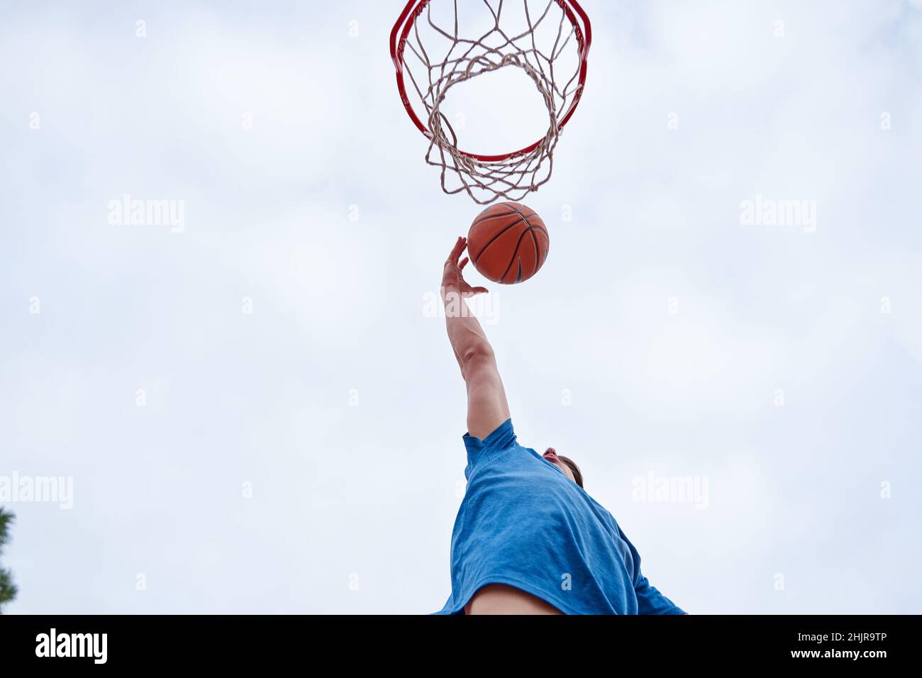young Caucasian man dunking on an outdoor basketball court. concept of ...