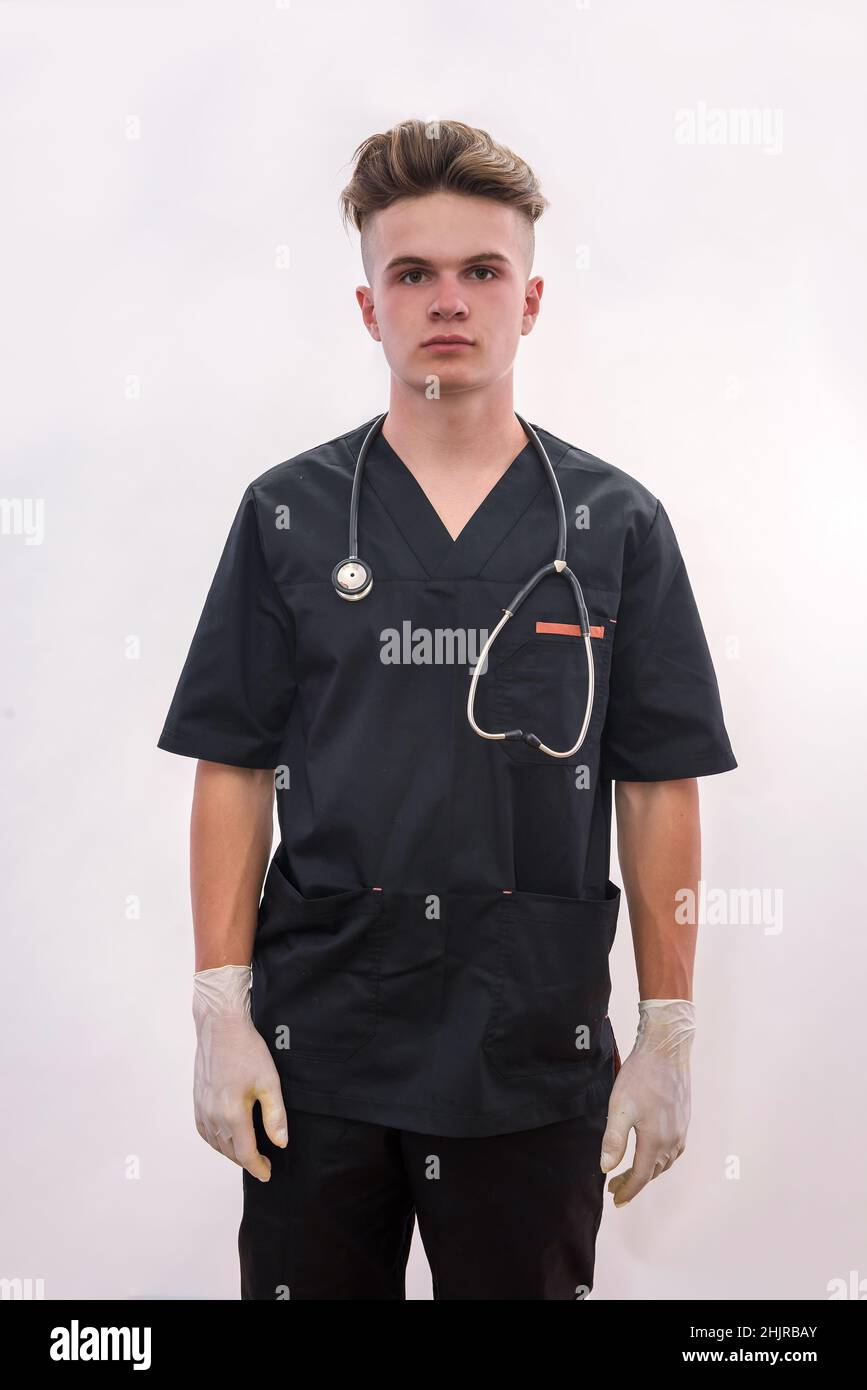 Young doctor with stethoscope in dark medical uniform posing isolated ...