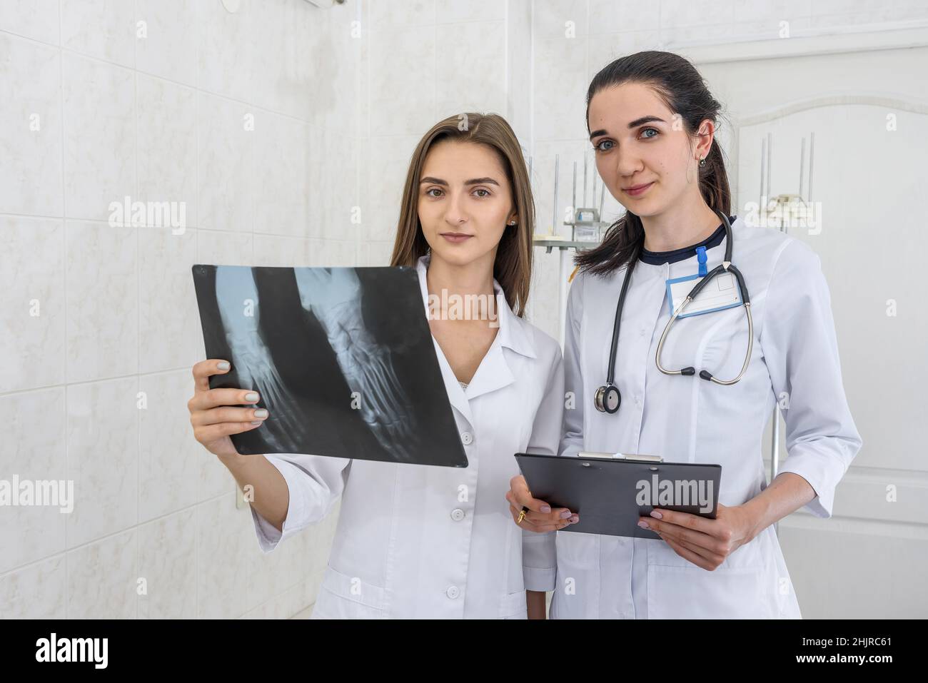 Doctor with intern examining patient's x-ray. Both wearing medical ...