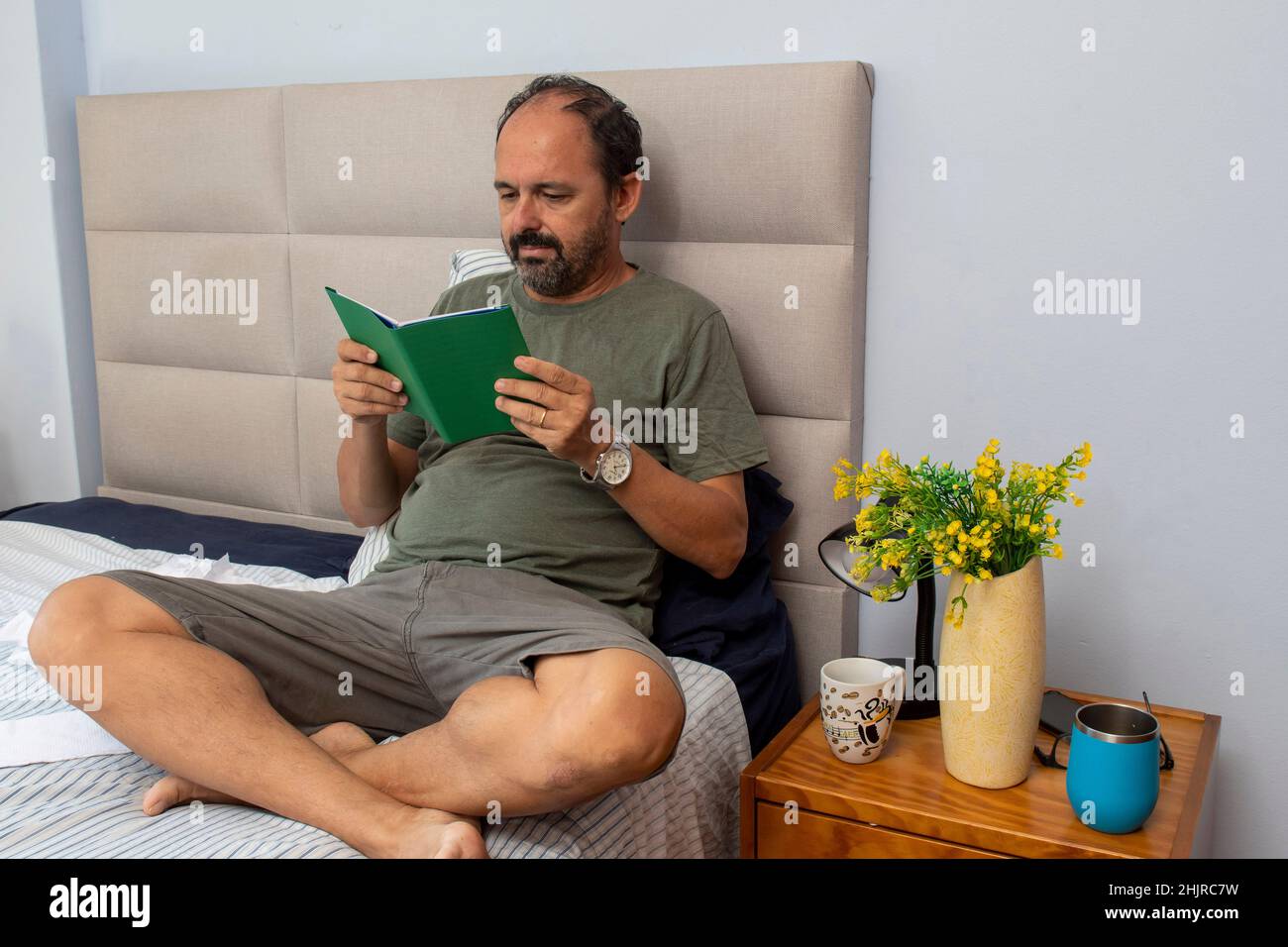gentleman sitting on bed in bedroom reading literature book Stock Photo ...