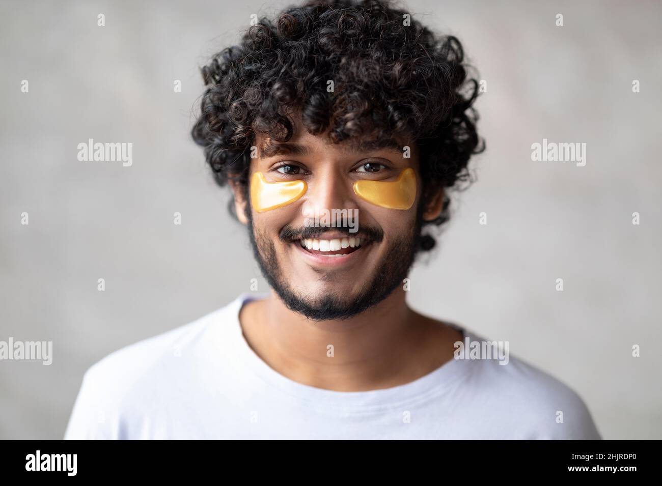 Modern beauty products. Portrait of handsome indian man with golden ...