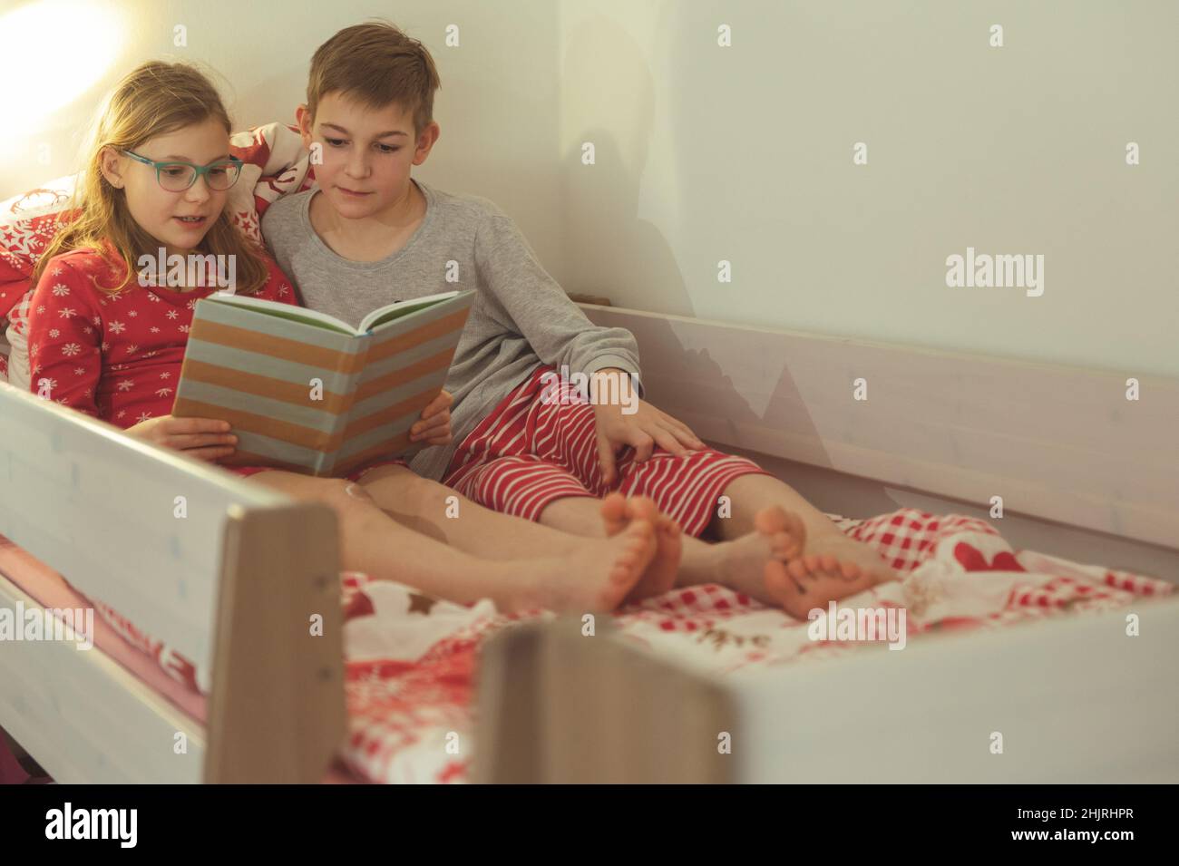 Teen brother and sister reading book in bed before night sleep Stock ...