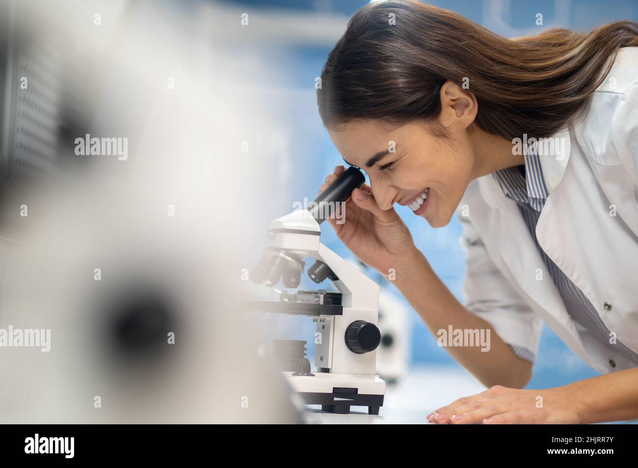 Profile of woman looking through microscope Stock Photo - Alamy