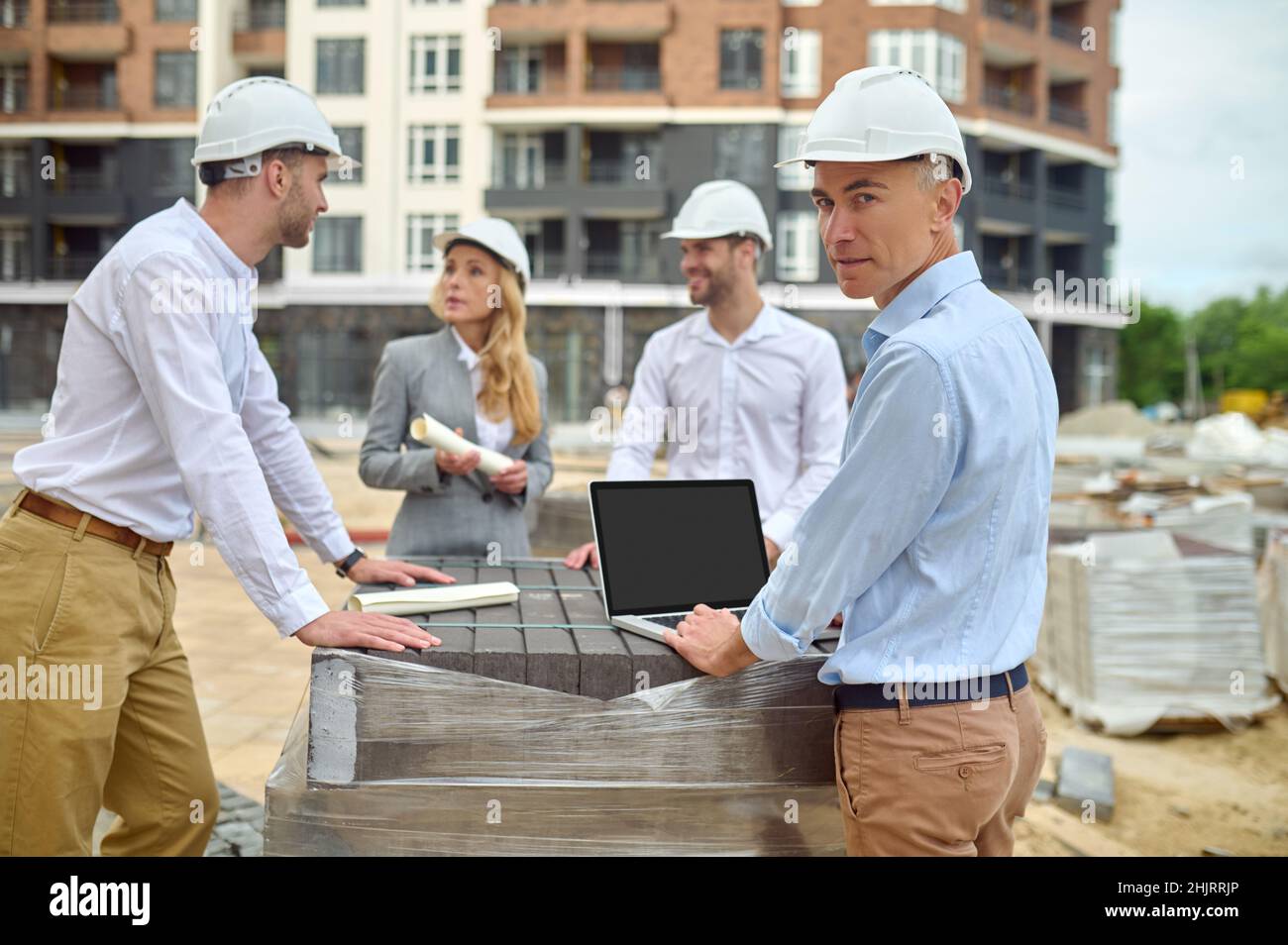 Builder standing among his three colleagues on the building site Stock ...