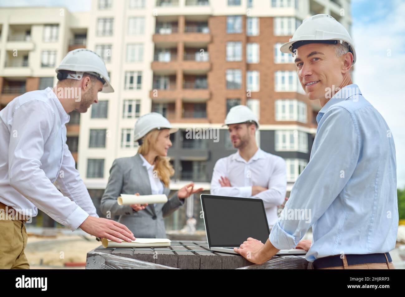 Worker standing among his three coworkers on the construction site ...