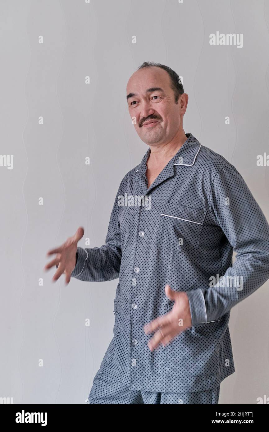 Dancing and singing happy senior Asian man in pajamas at home against ...