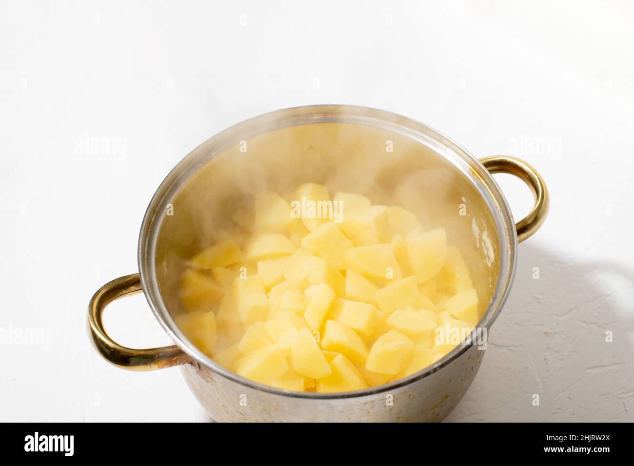 Boiled potatoes in a pot. Hot potato cubes with a piece of butter ...