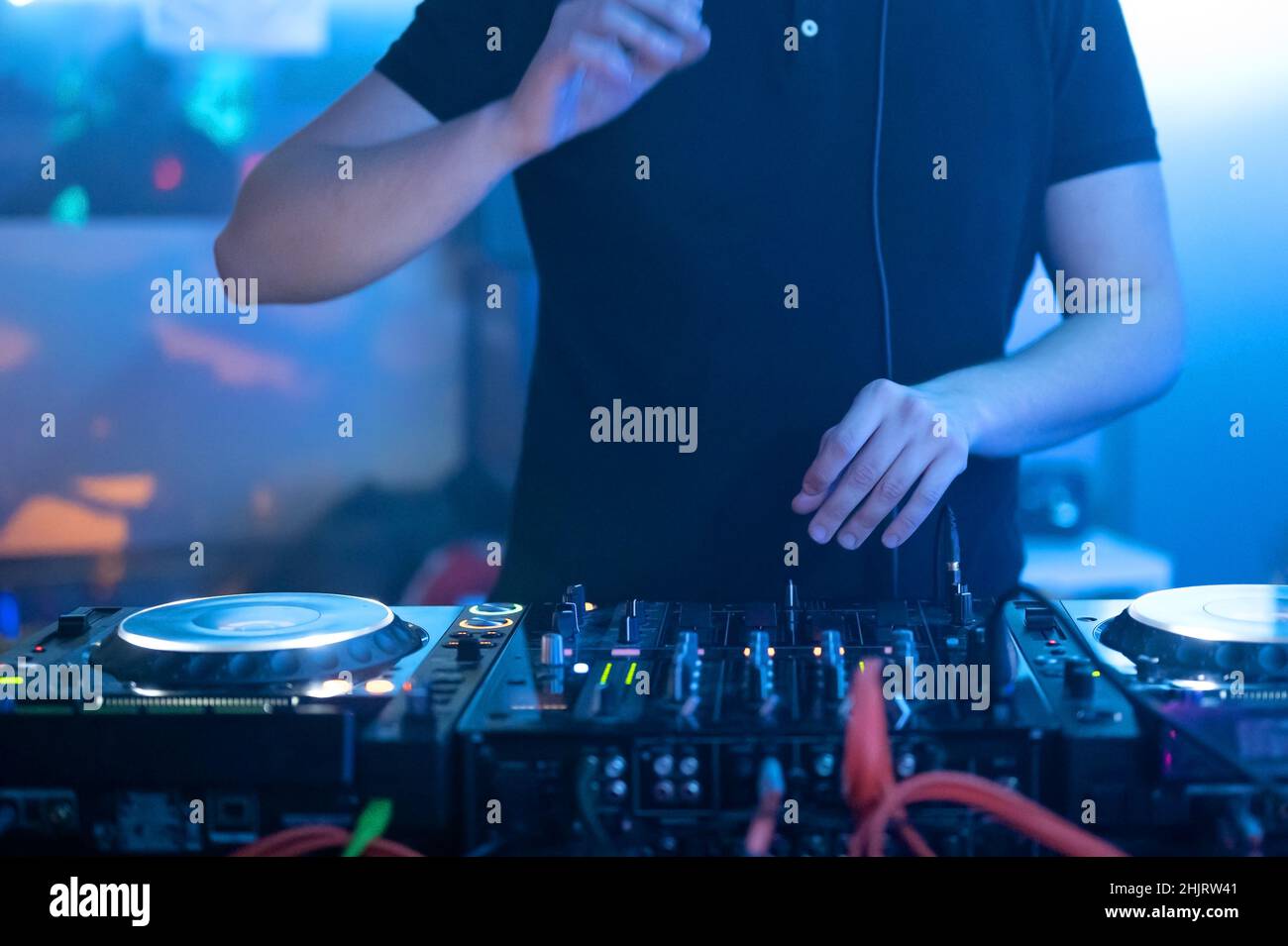 Close up Front view of of DJ hands controlling a music table in a night ...