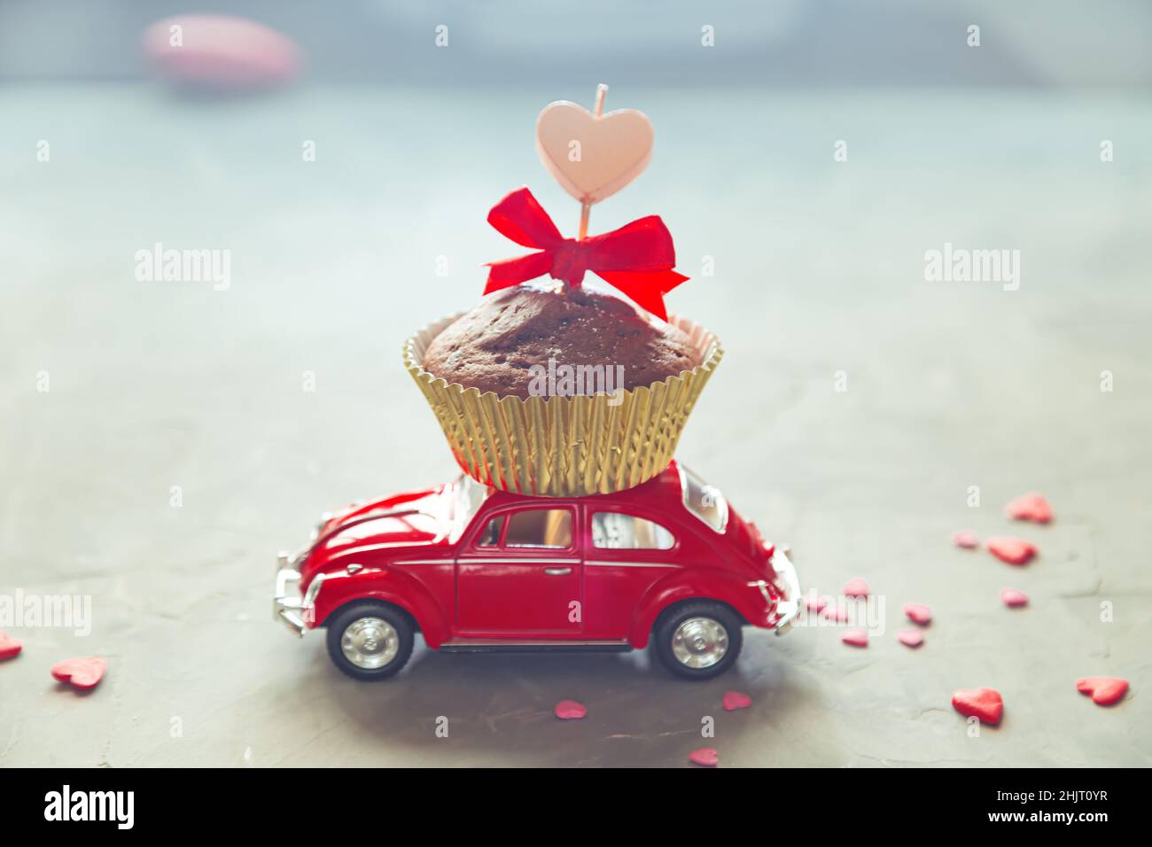 Red retro car carries a chocolate cupcake with a heart-shaped candle ...