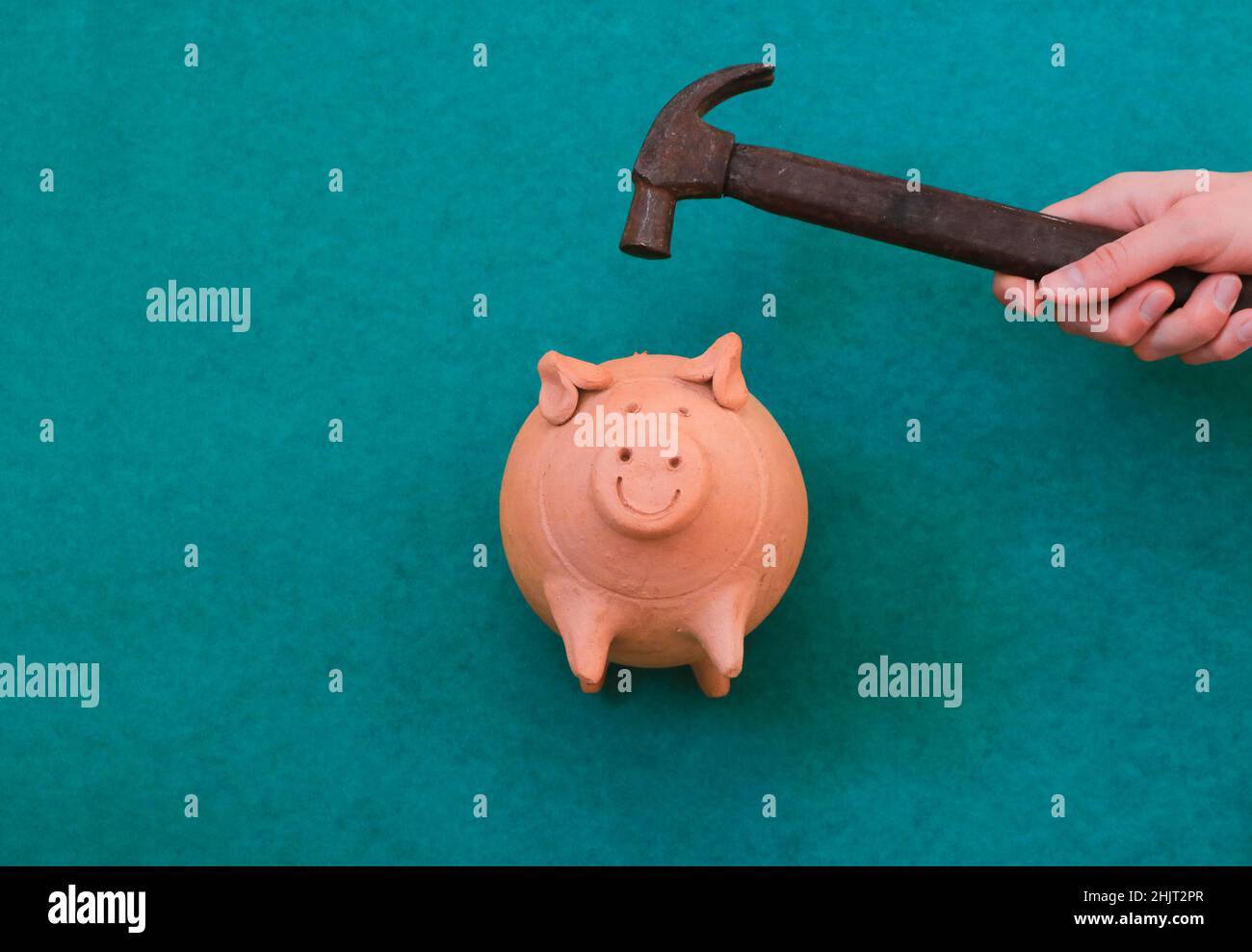 Hand Holding a Hammer Breaking pig coin isolated on green background ...