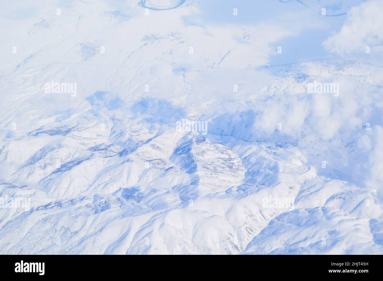 A magnificent aerial view of clouds and snow-covered mountains from an ...