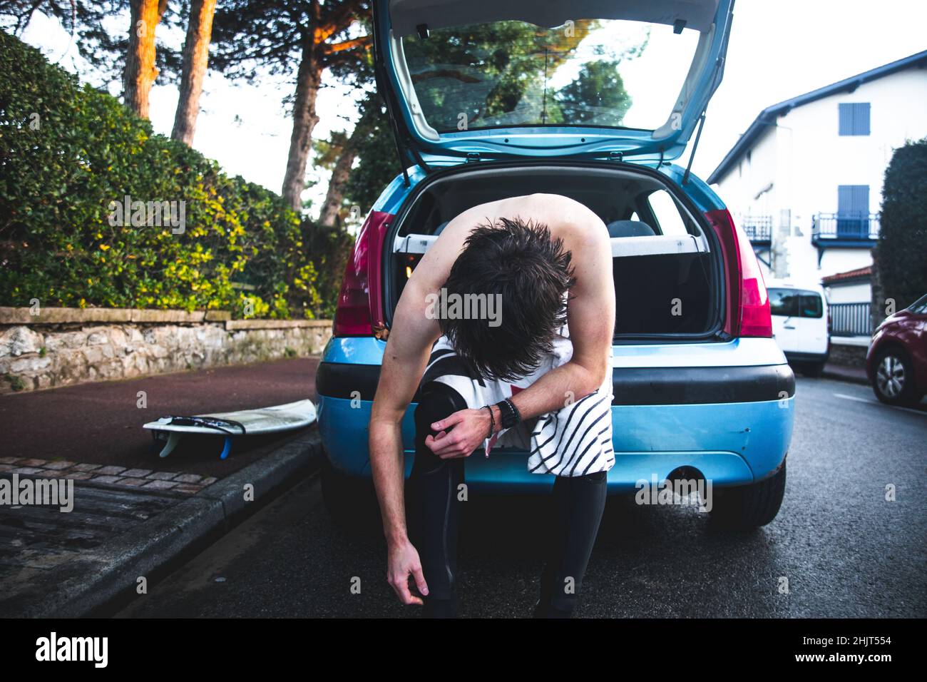 Young caucasian man changing clothes on the car trunk after surfing at ...